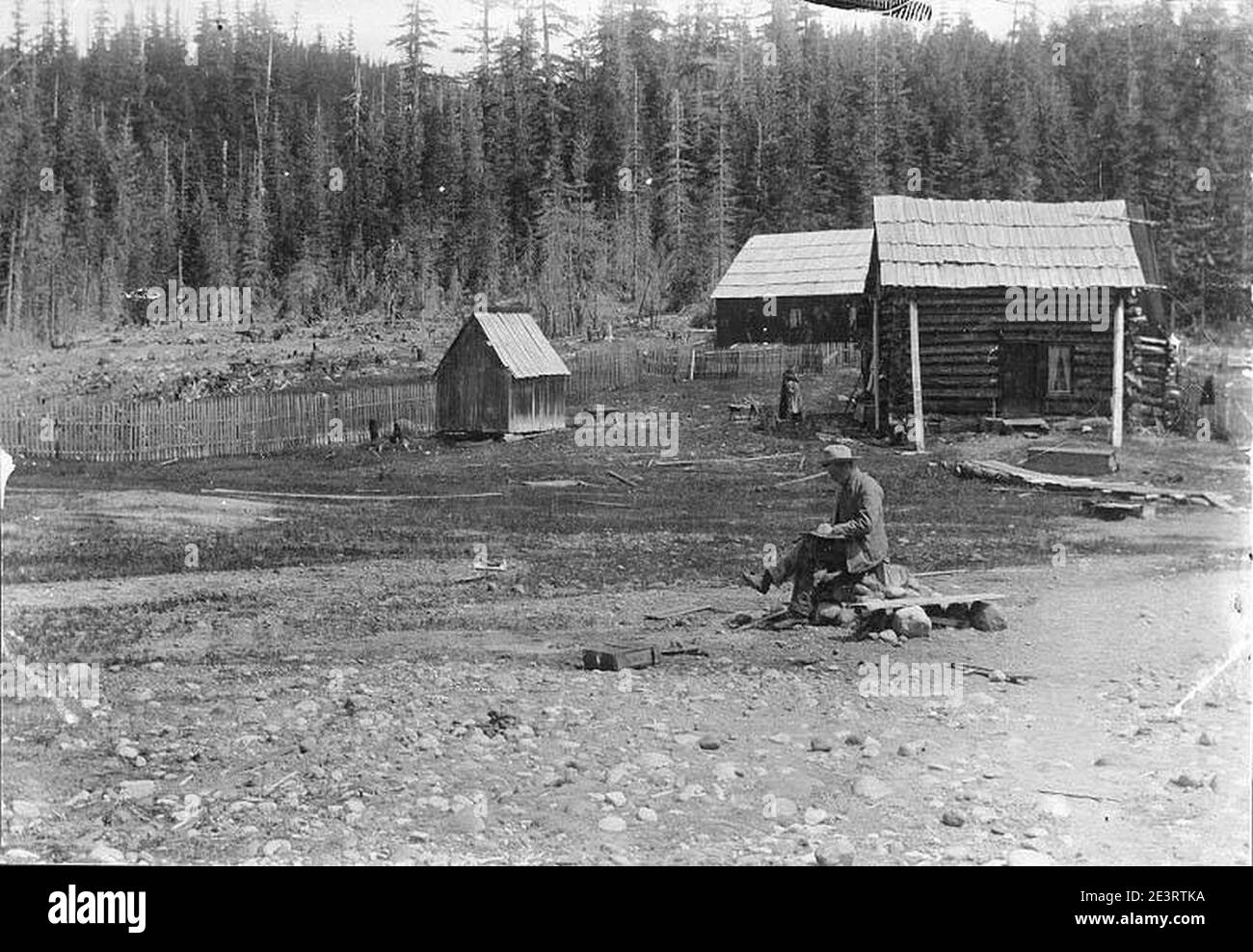 Man sitting in front of a log cabin at Longmire Springs, ca 1897 ...