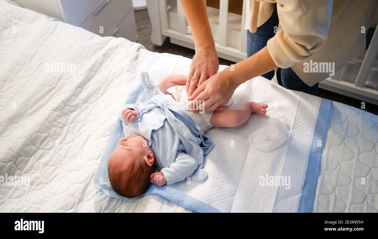 Top view of young caring mother changing messy diapers of her newborn ...