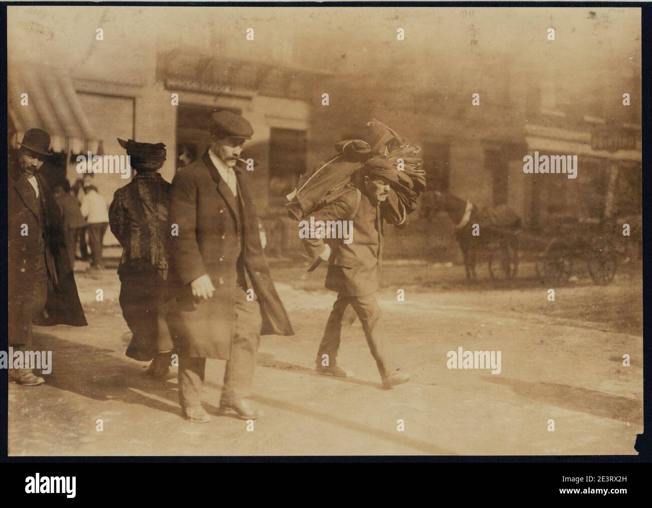 Man straining to carry heavy bundle of clothing. They carry these for ...