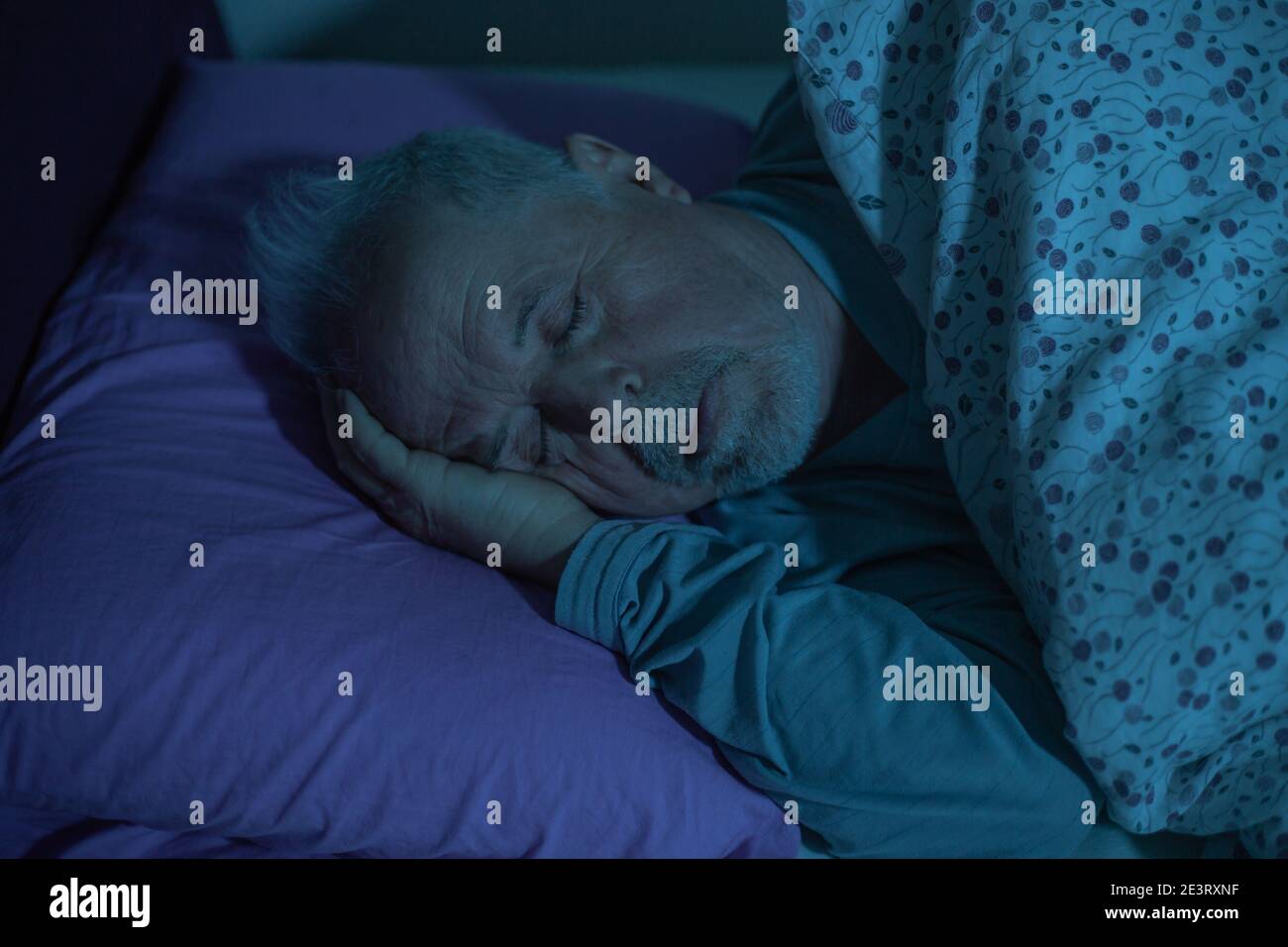 Senior man sleeping in the middle of the night in a bed, deep sleep ...