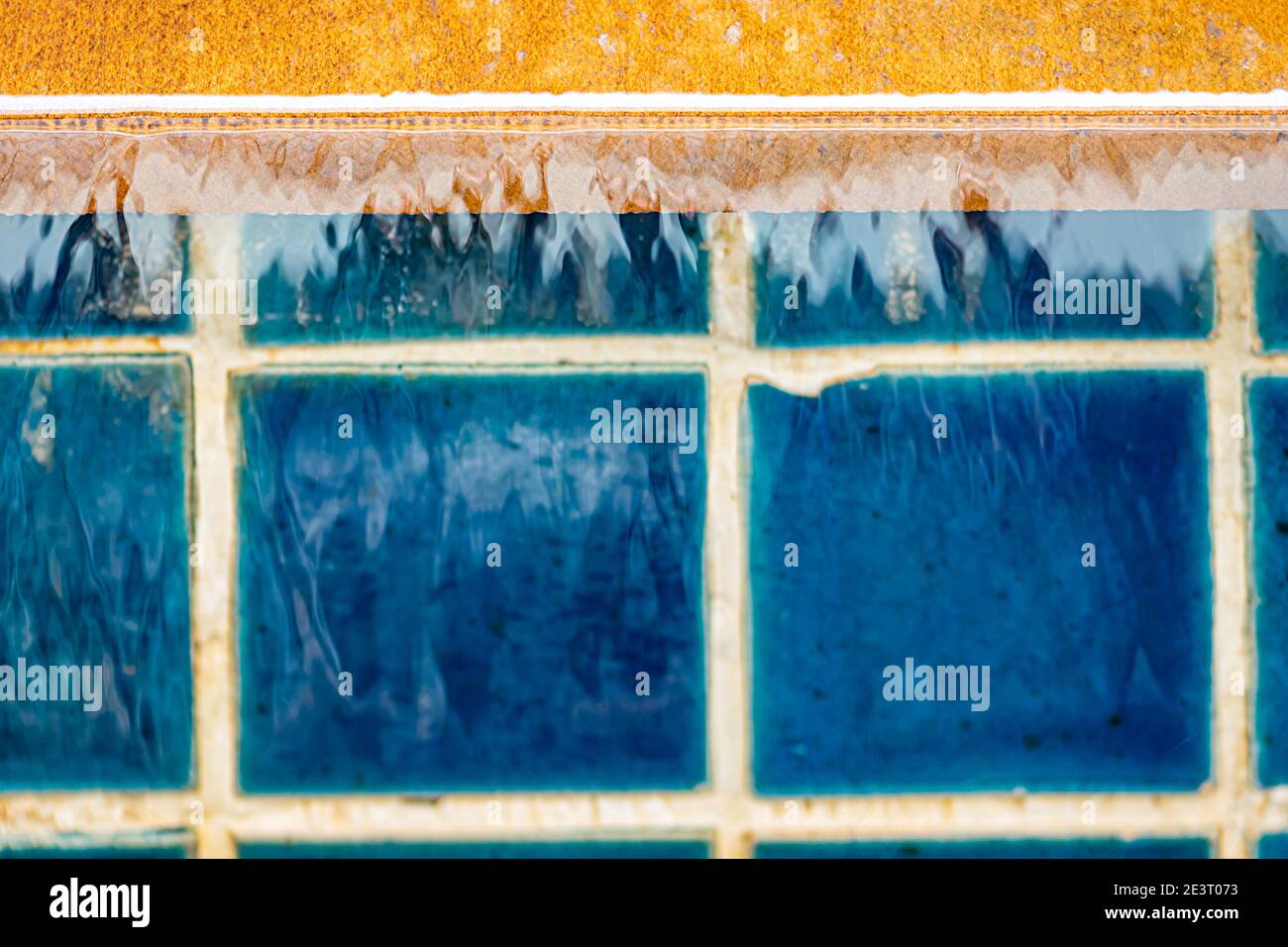 Running pool water in blue and yellow bricks background. Background is ...