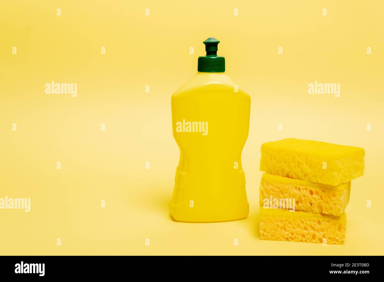 Yellow sponges and bottle of dishwashing liquid with cap on yellow ...