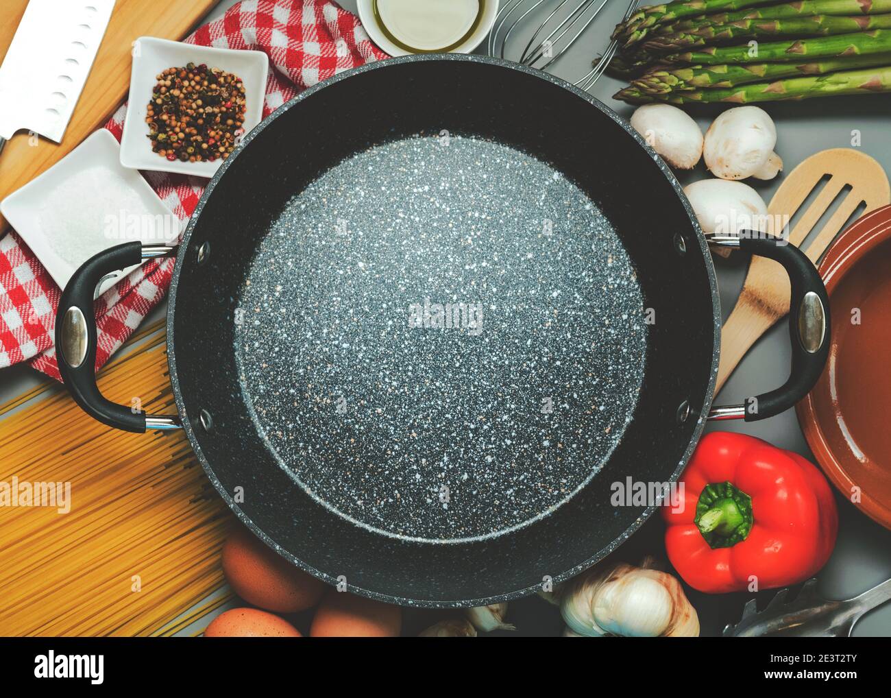 Top view of empty frying pan with ingredients for cooking on grey ...
