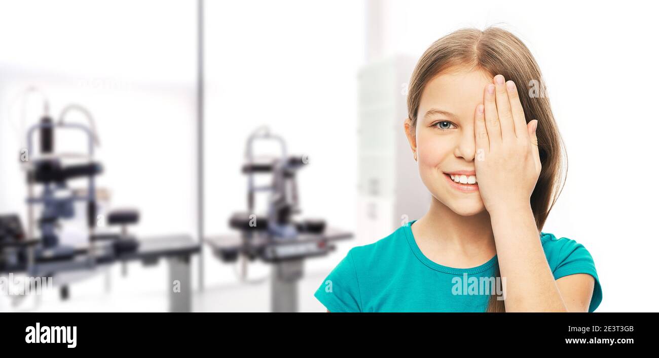 Smiling teen girl closing eye with her hand for checking vision, over ...