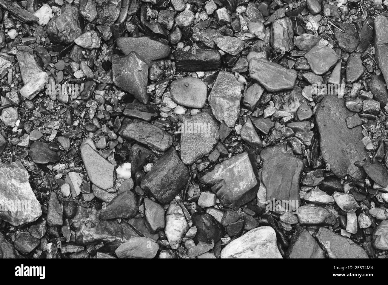 top-down view of various lose and sharp rocks on the ground in black ...