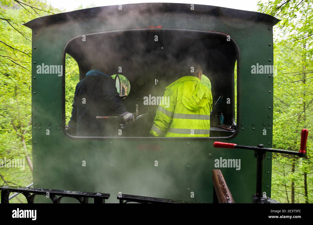 Steam train driver and fireman during their work. Back view. Closeup of ...