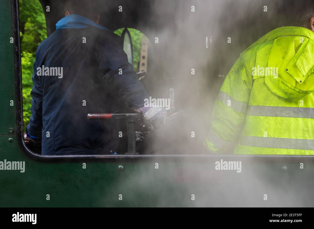 Steam train driver and fireman during their work. Back view. Closeup of ...