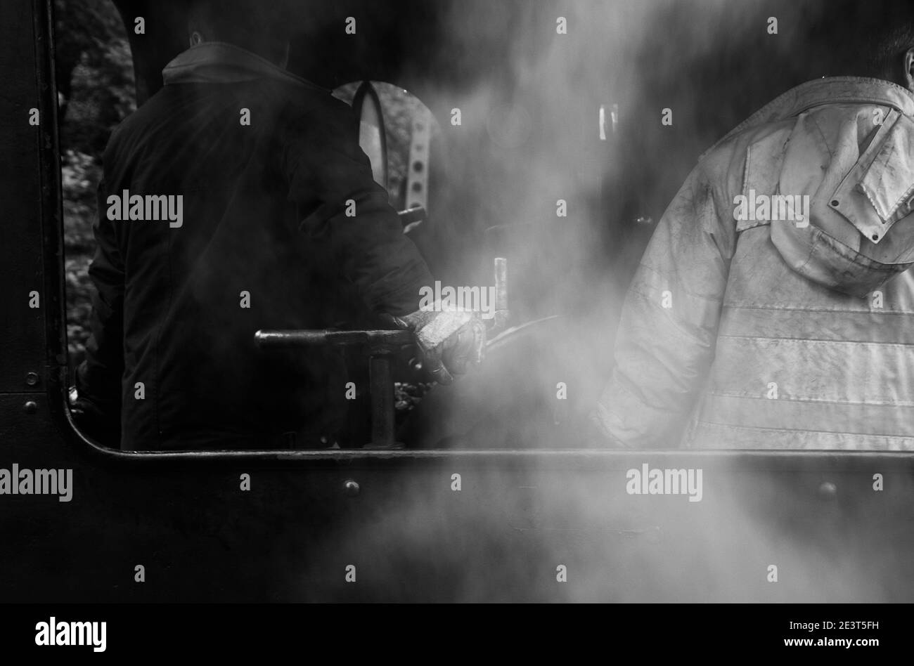 Steam train driver and fireman during their work. Back view. Closeup of ...