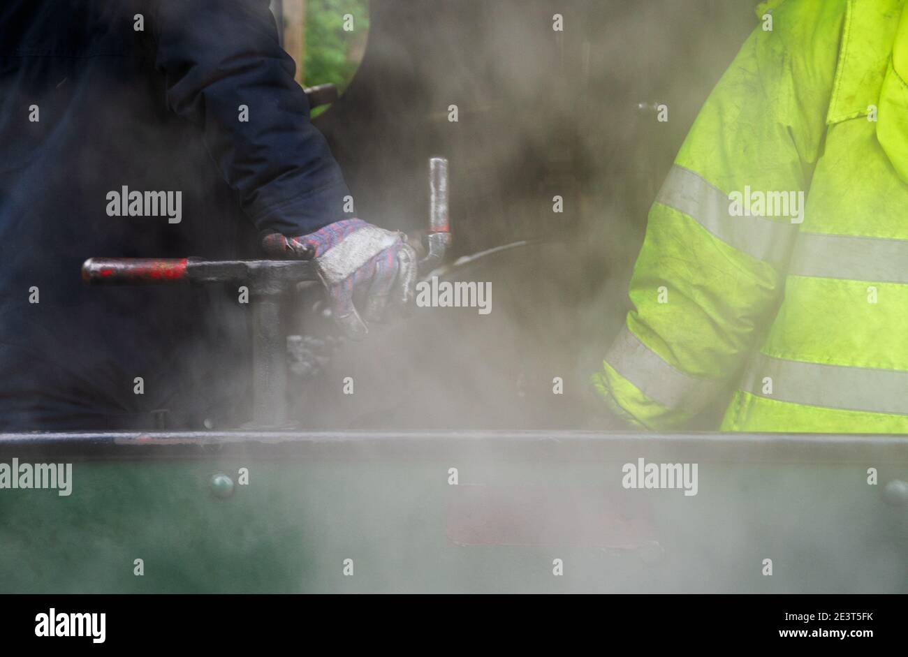 Steam train driver and fireman during their work. Back view. Closeup of ...