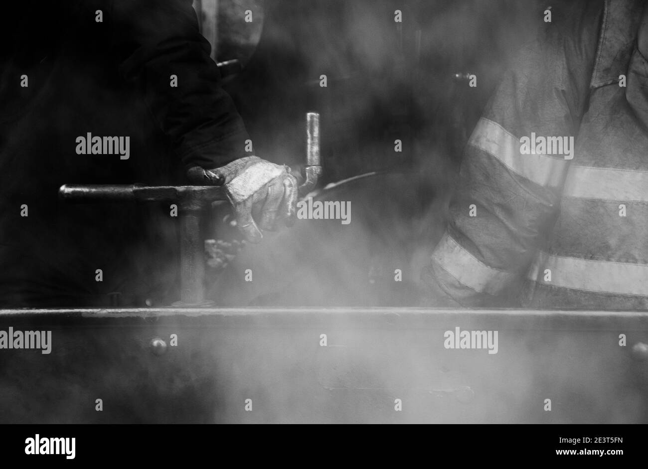 Steam train driver and fireman during their work. Back view. Closeup of ...