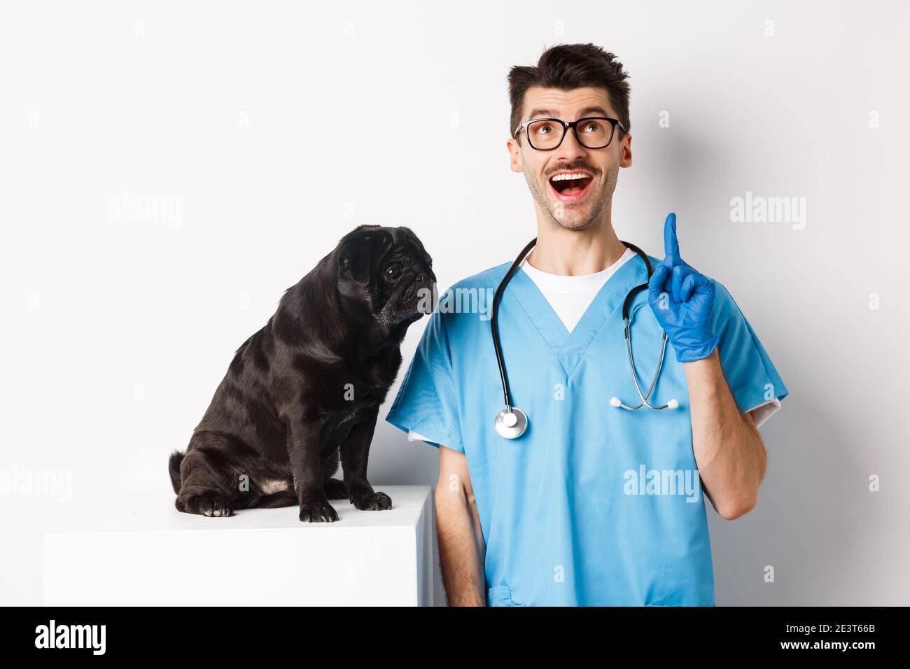 Handsome young doctor at vet clinic pointing finger up and looking ...