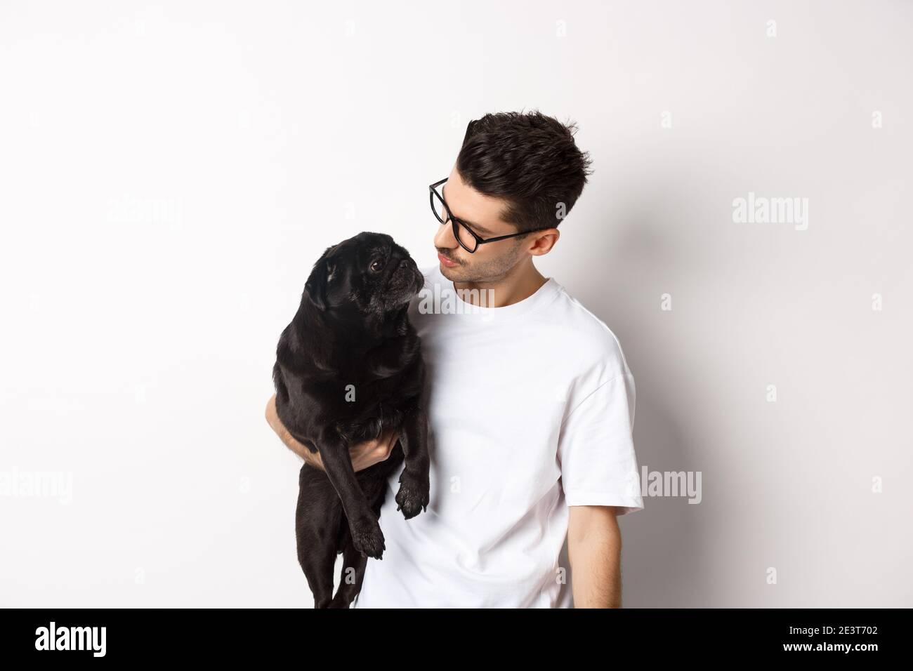 Handsome young man holding his black pug, dot and pet owner looking ...