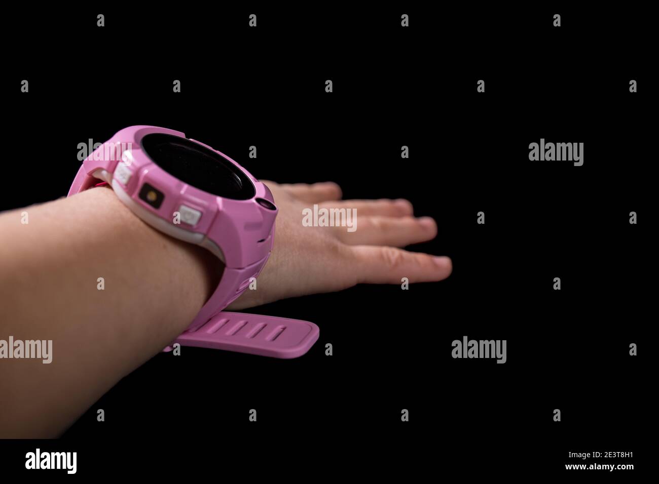 Children's hand with pink smart watch isolated on black background ...
