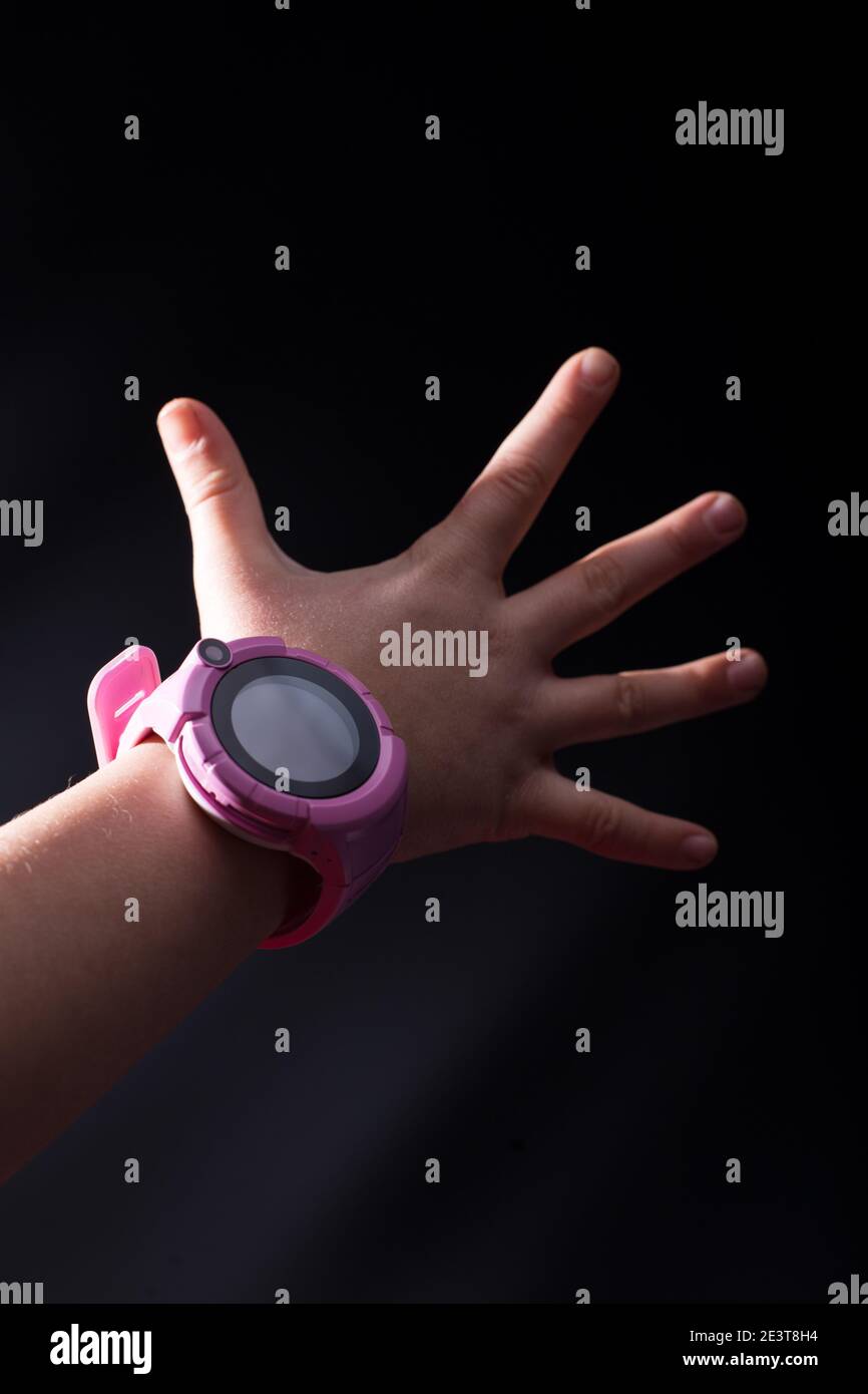 Child hand with pink smart watch close up, on black background Stock ...