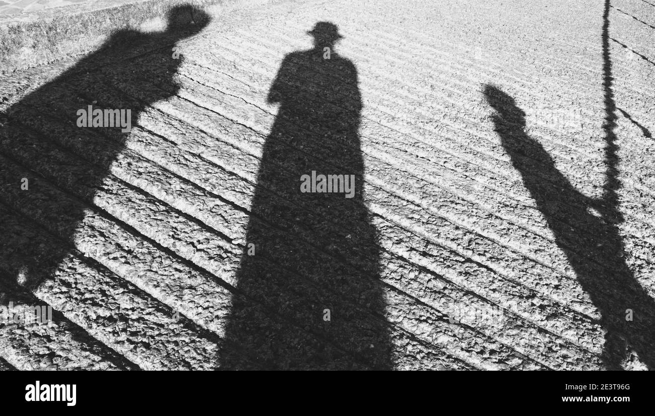 Three people shadows on striped cement surface. Two person standing and ...