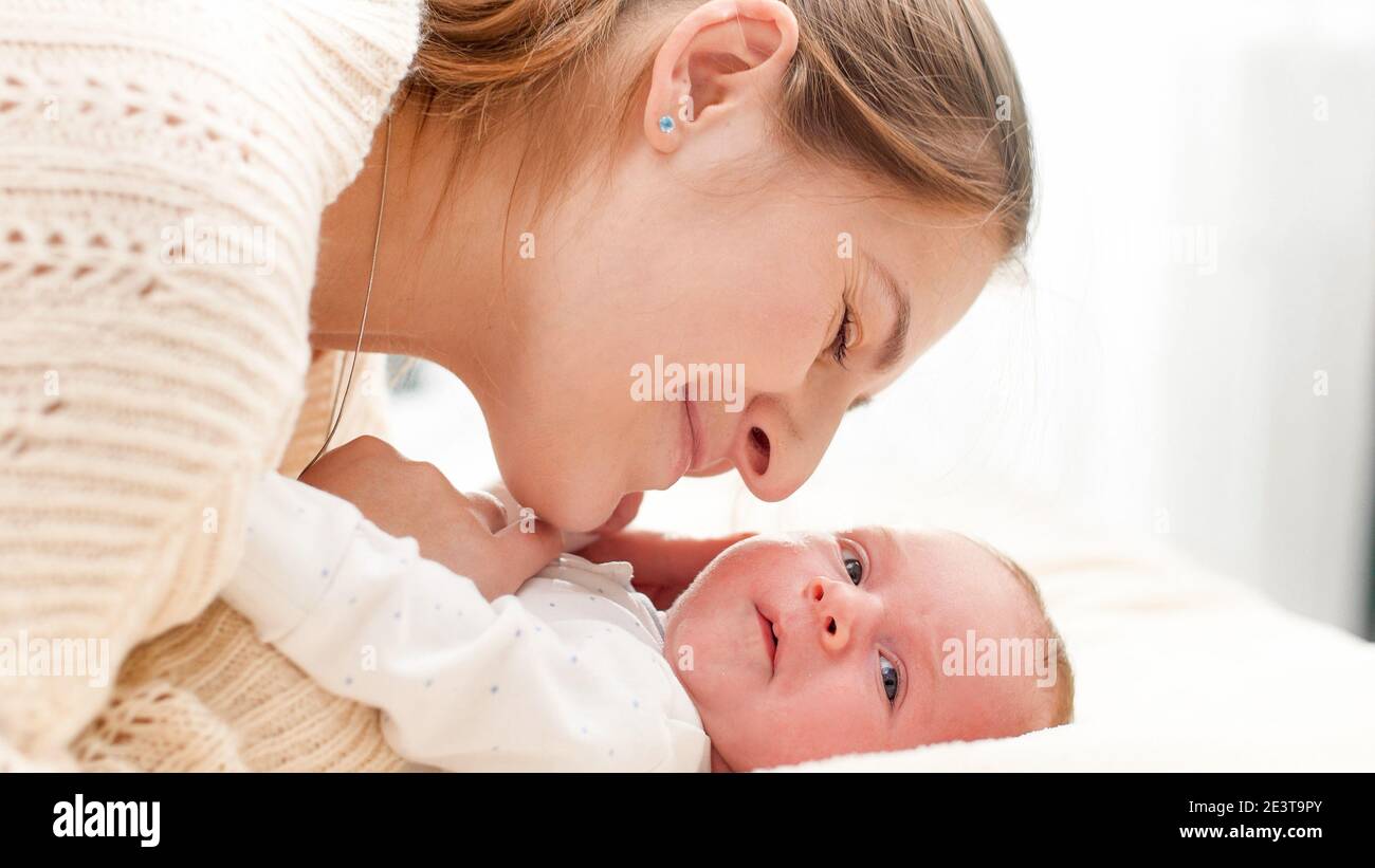 Closeup portrait of smiling young mother looking on her newborn baby ...