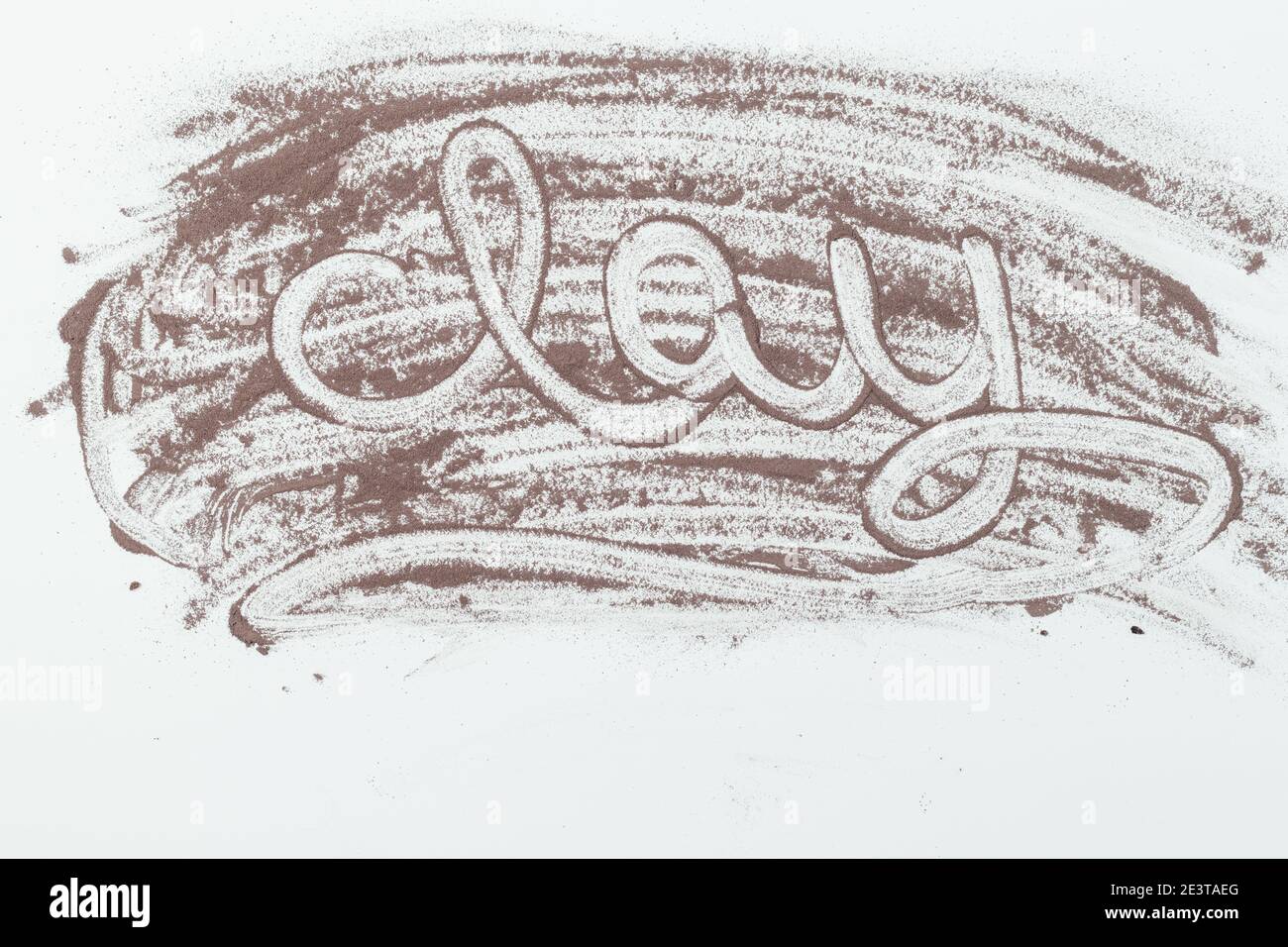 Word clay written on scattered black clay cosmetic powder on white ...