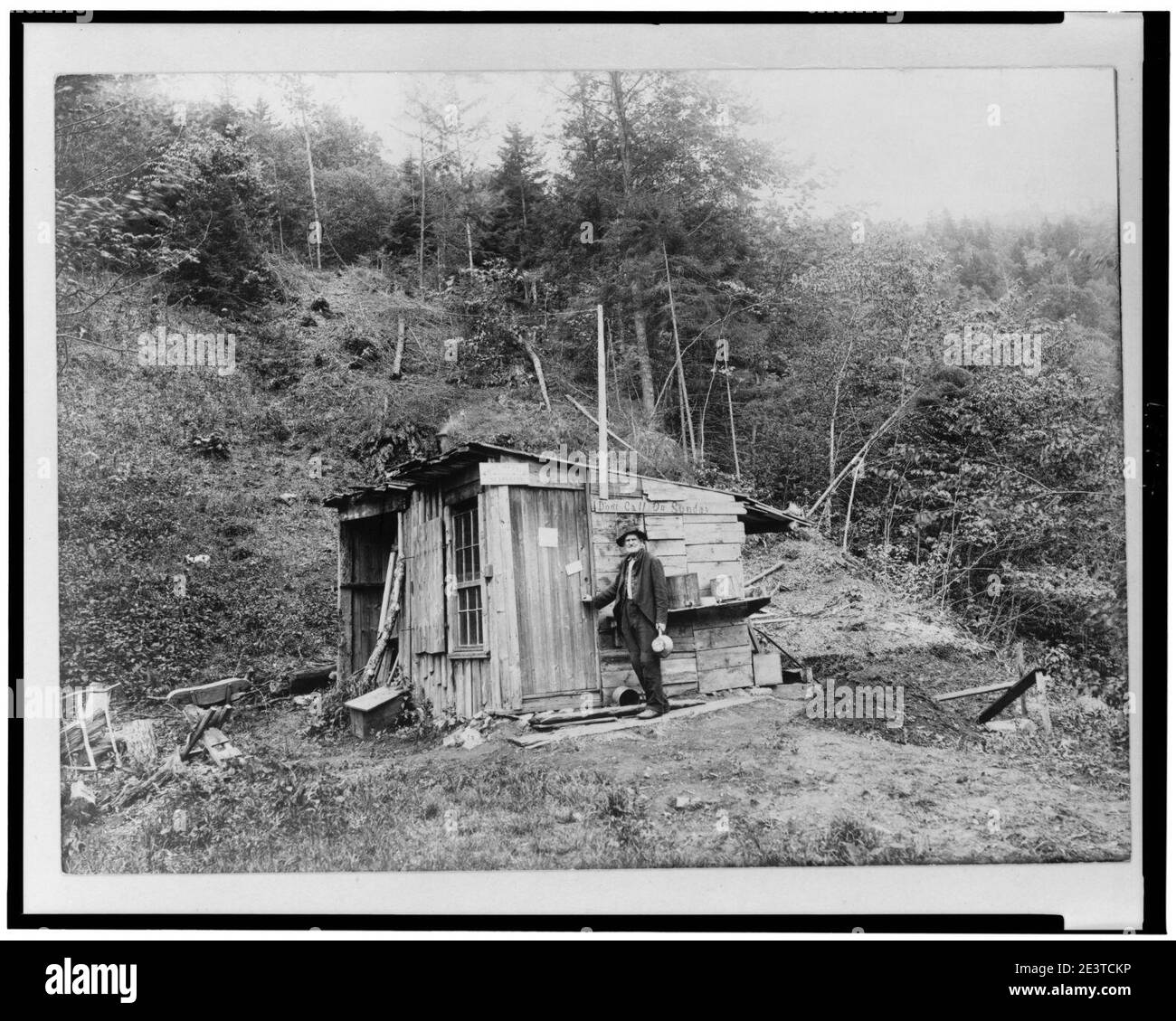 Man, identified as the postmaster, standing outside of shack serving as ...
