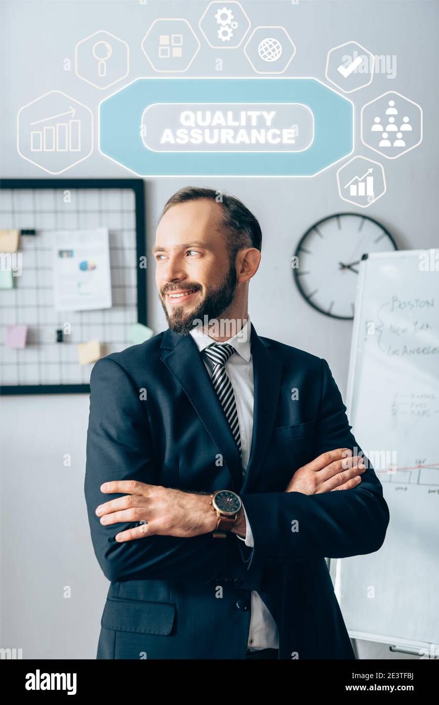 Smiling investor with crossed arms looking away near quality assurance ...