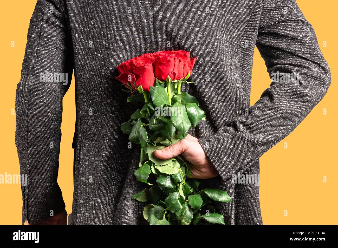 Man with a bouquet of red roses behind his back. Elegant man holding ...