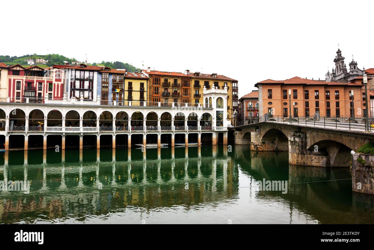Tolosa town. Colorful buildings, market and bridge, reflection in river ...