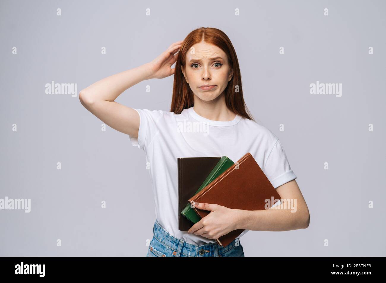 Confused young woman college student holding book and crying on gray ...