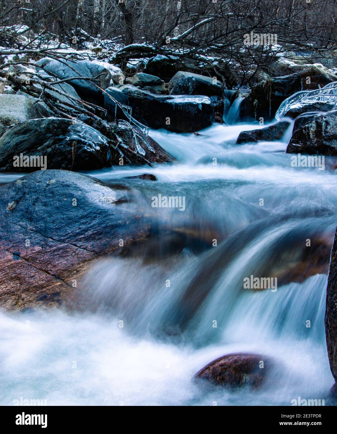 Mountain river frozen in winter with very cold blue water. The water ...