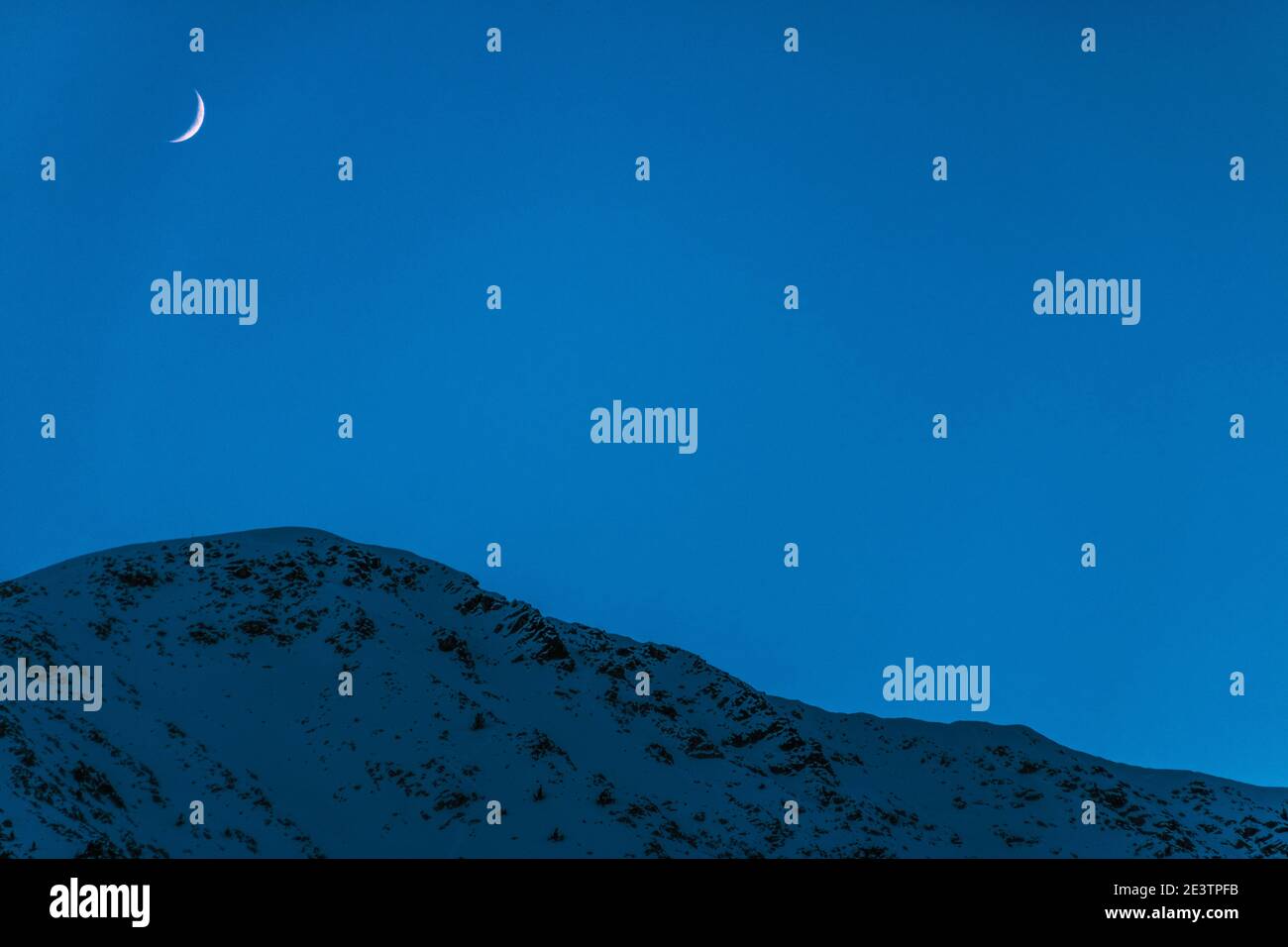 Snowy mountain peaks with the moon at blue hour. Nature background ...