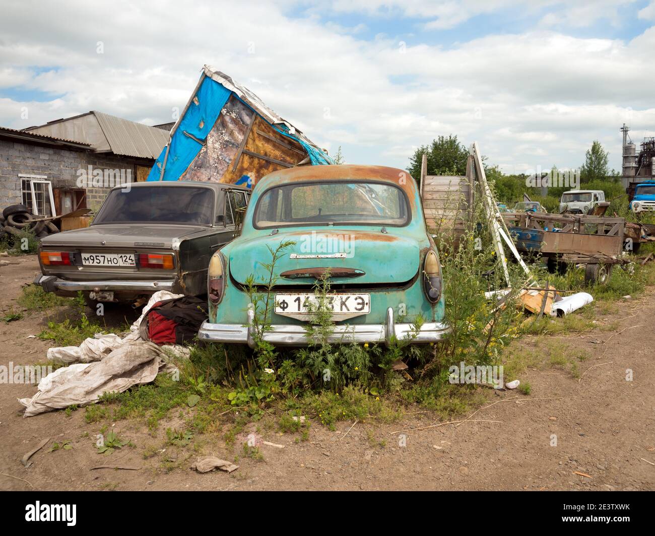 Old rusty cars are thrown in a junkyard among the garbage in the summer ...