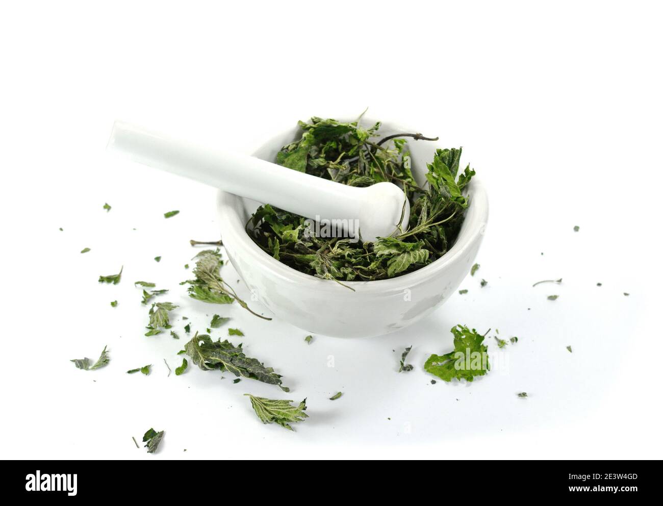 Closeup of dried nettle in a mortar with pestle, isolated on white ...
