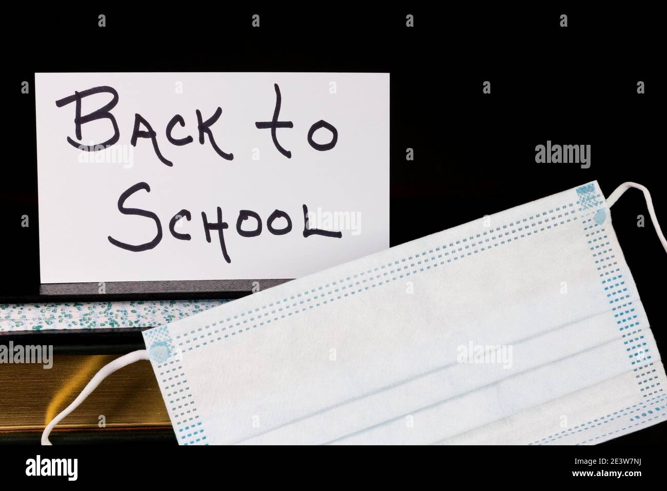 Back to School handwritten on white note card with face mask and books ...