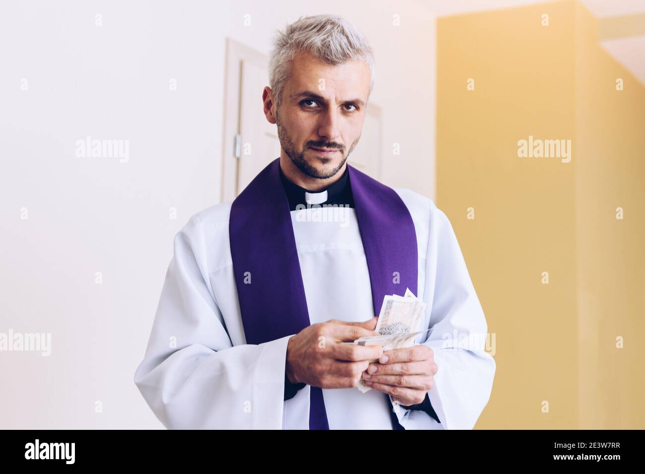 Polish catholic priest holding and counting money during pastoral visit ...