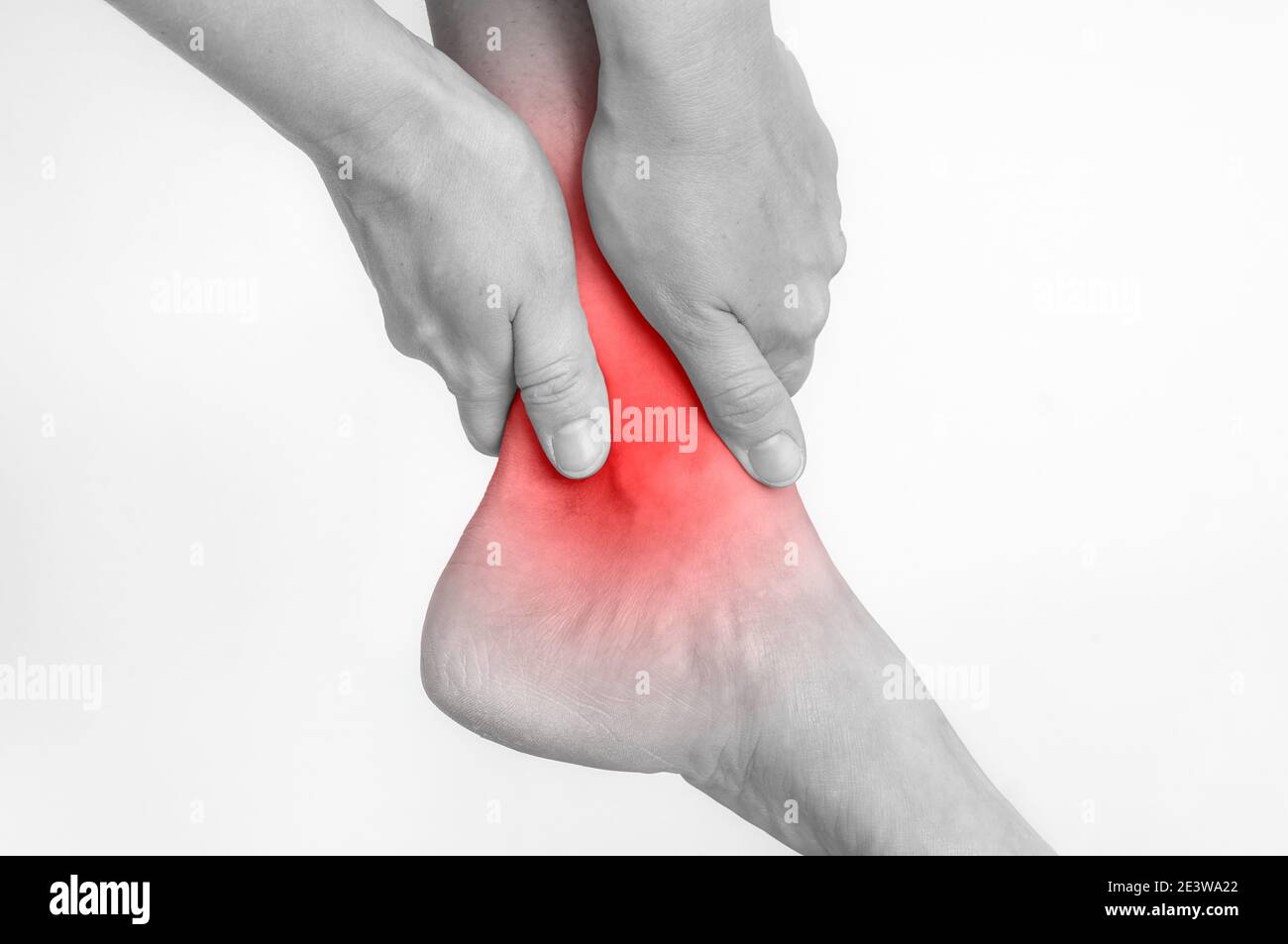 Woman with ankle pain holding her aching leg - black and white photo ...