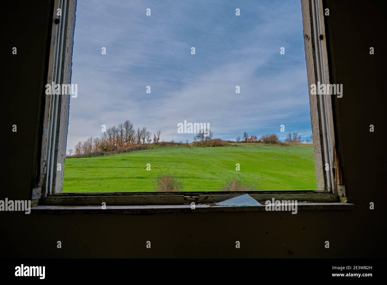 Old type window made of wood with scene of small hill covered by green ...