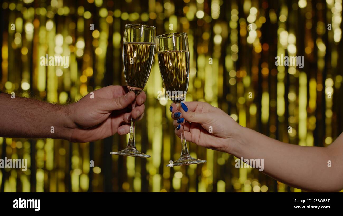 Two hands with glasses of champagne making cheers on gold background ...