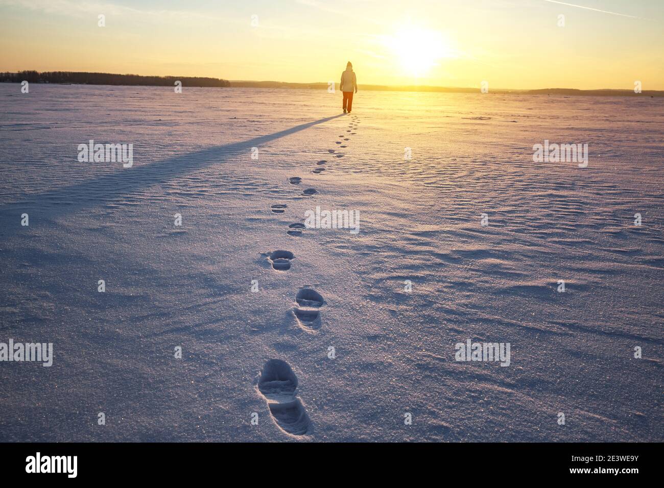 Footprints in the snow. The girl leaves towards the sunset Stock Photo ...