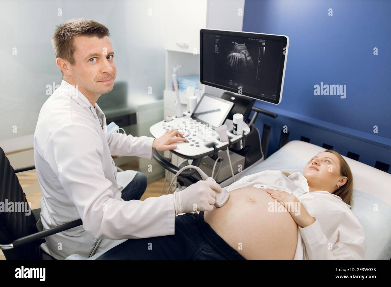 Smiling Man Obstetrician Examining Pregnant Belly By Ultrasonic Scan