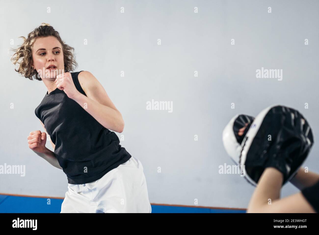 Close-up of barefoot woman leg practicing kicking with taekwondo coach ...