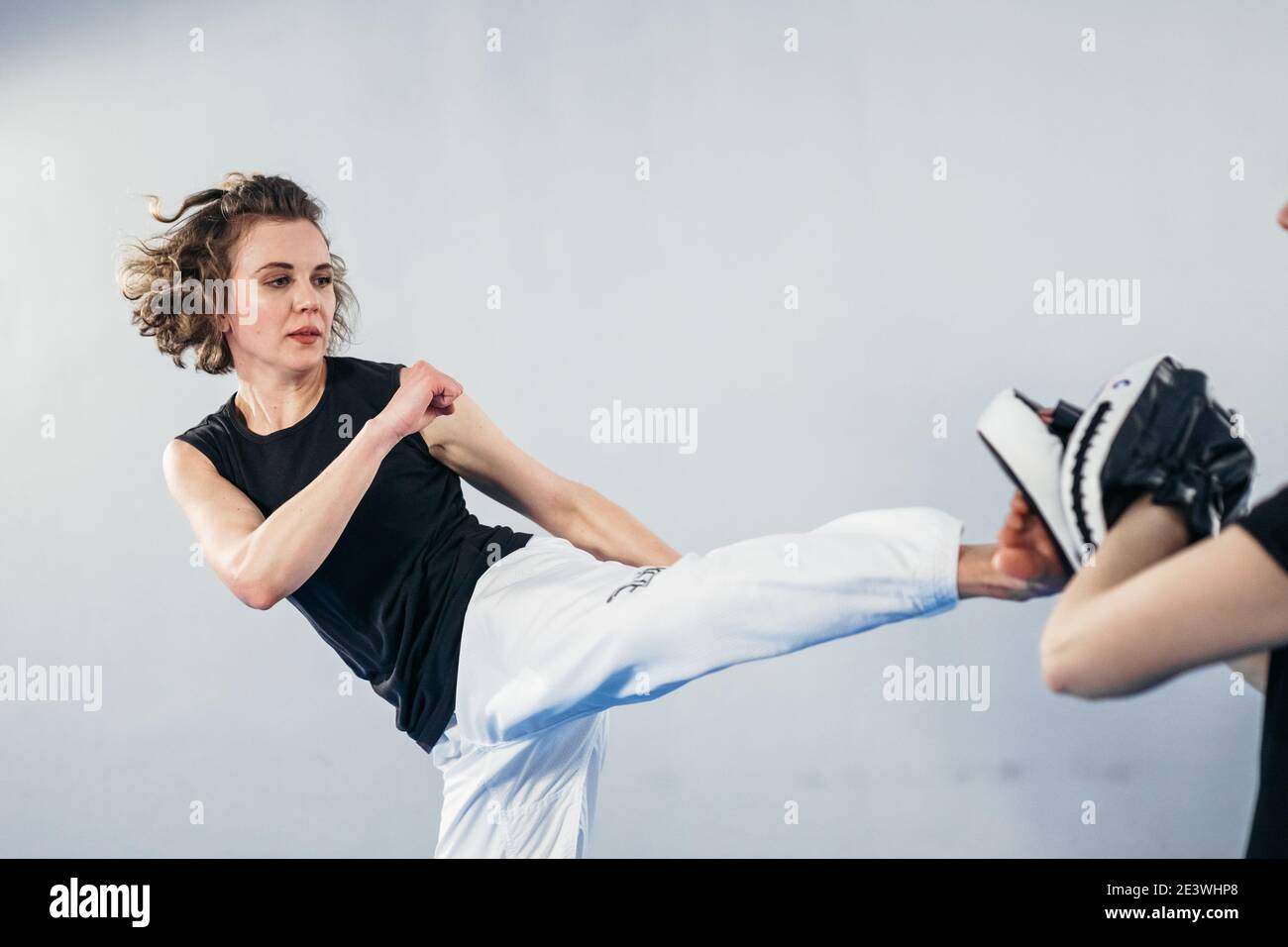 Female martial arts fighter practicing with trainer, punching taekwondo ...