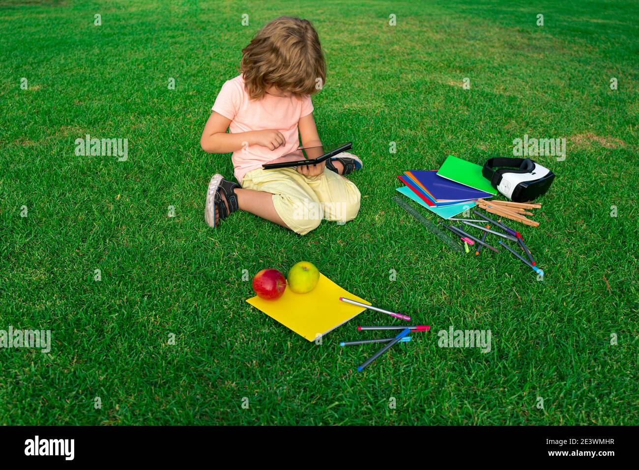 Kid with tablet sit on grass in park. Kids education, learning and ...