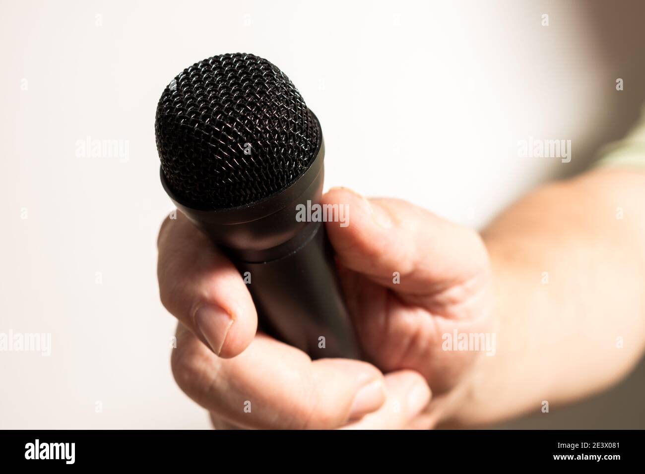 A man's hand holding a black microphone. Concept of communication ...