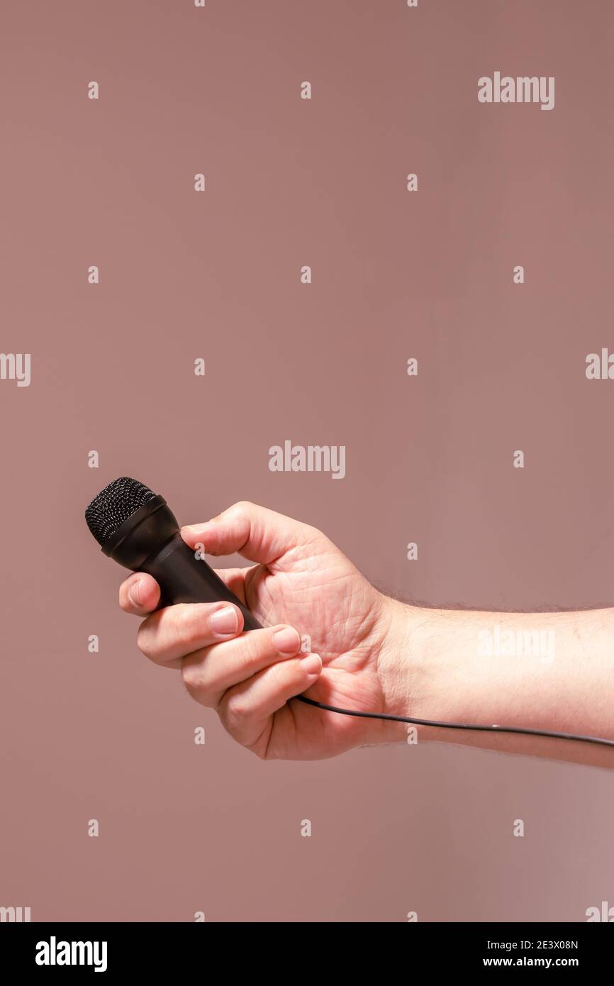 A man's hand holding a black microphone. Concept of communication ...