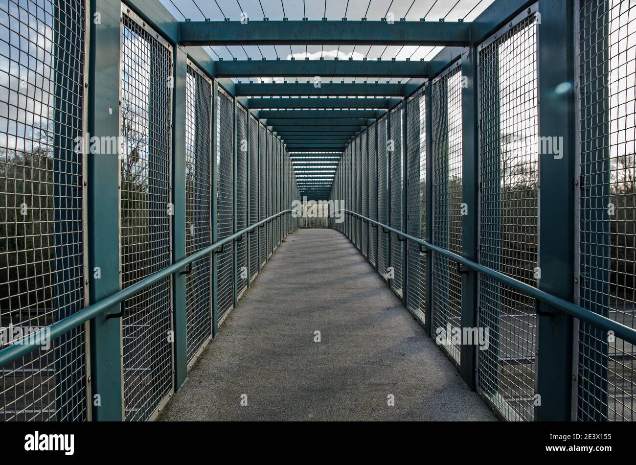 View along the inside of a caged footbridge over the M3 motorway in ...