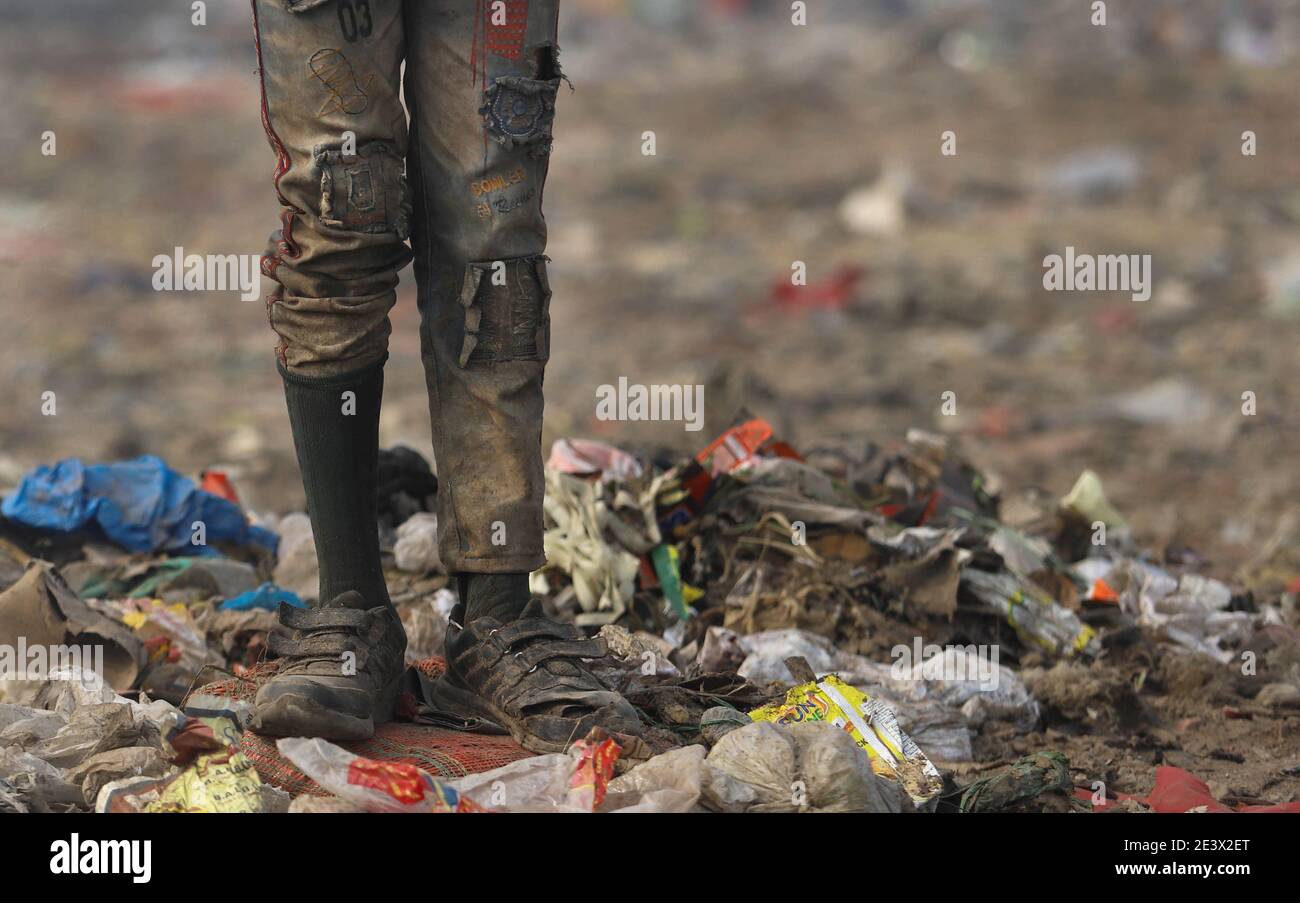 Neu Delhi, India. 18th Jan, 2021. A young rag picker stands collecting ...