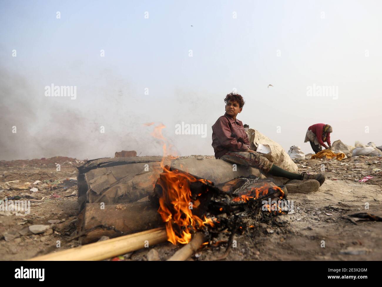 Neu Delhi, India. 18th Jan, 2021. A young rag picker sits out the ...