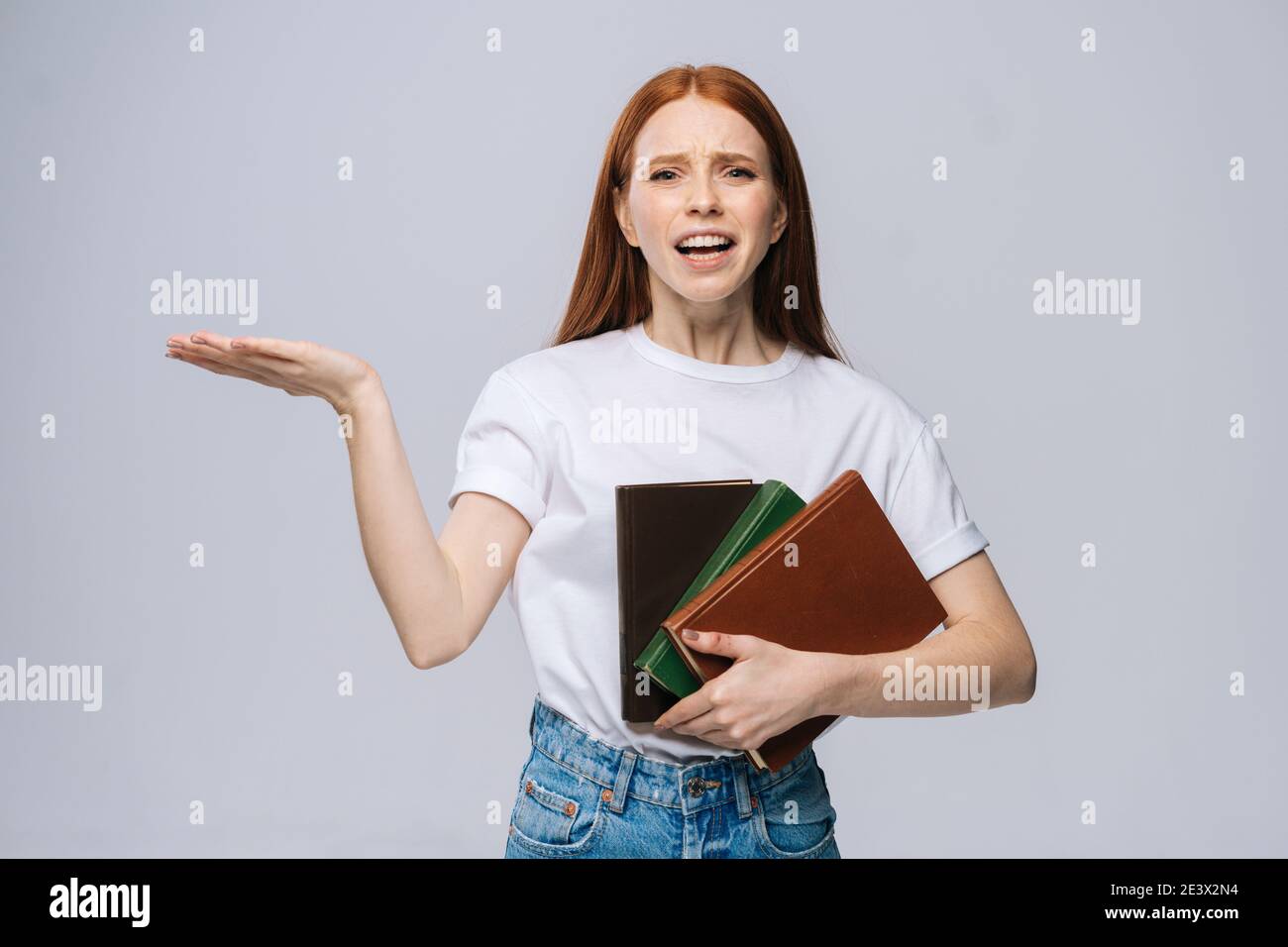 Angry young woman college student holding book and screaming crying ...