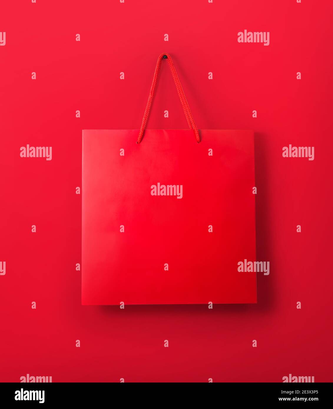 Mockup of red paper shopping bag with handles on the red color ...