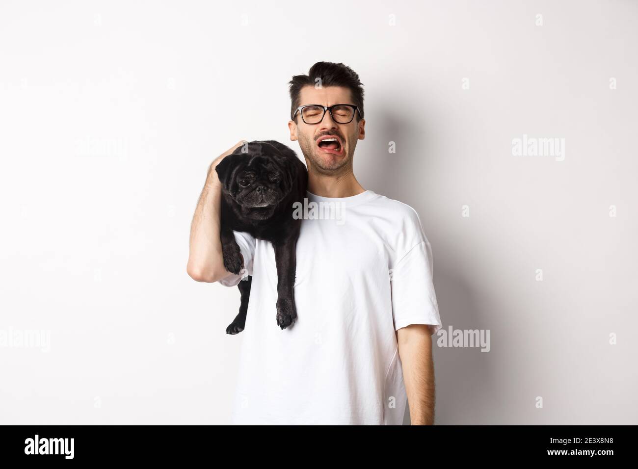 Sad dog owner crying, holding cute black pug on shoulder and looking ...