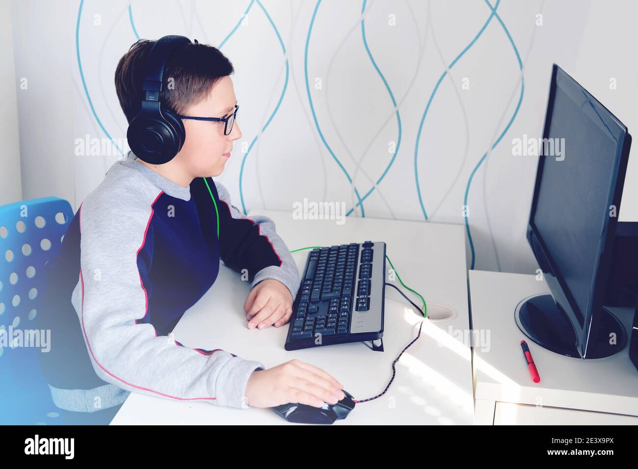 teenager boy in glasses looking at computer monitor. distance learning ...