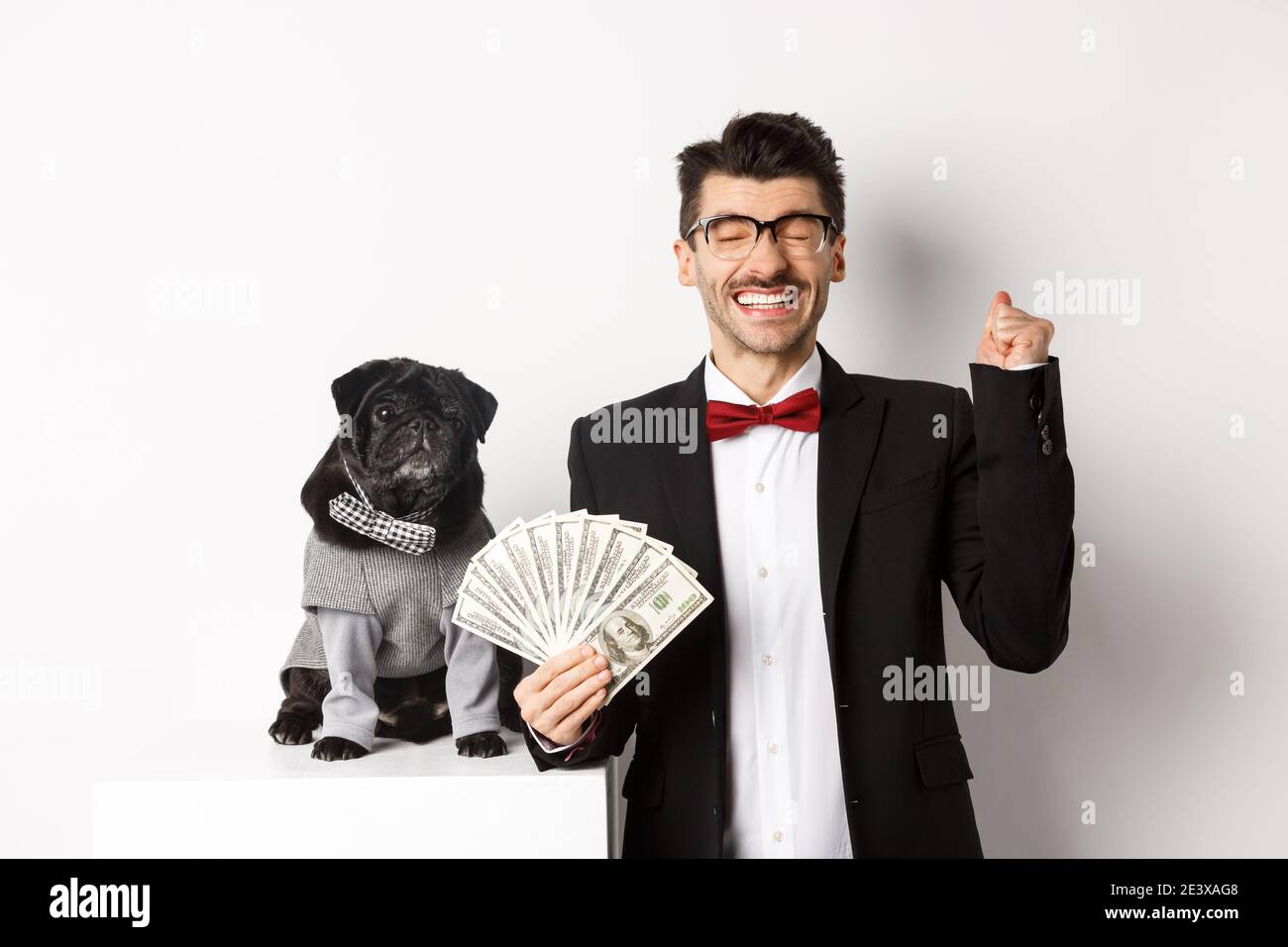 Happy young man and cute black dog standing in party costumes, pug ...